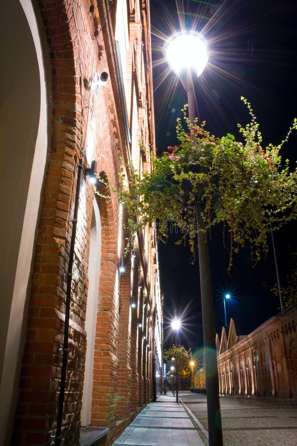 Vertical Shot of a Sidewalk Surrounded by Buildings and Lamps at Night ...