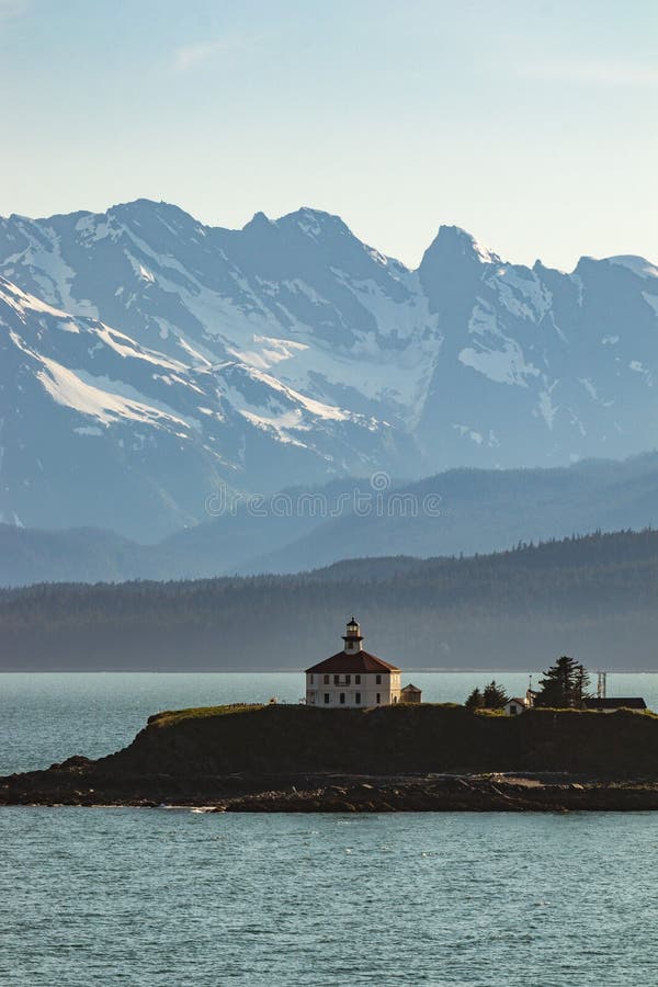 Vertical Shot of a Small Island with a Lighthouse Against Snowy ...