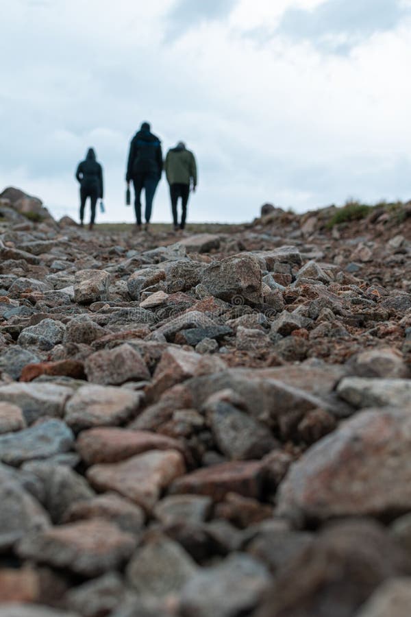 Vertical Shot of Small Stones and a Group of Hikers Going Up the ...