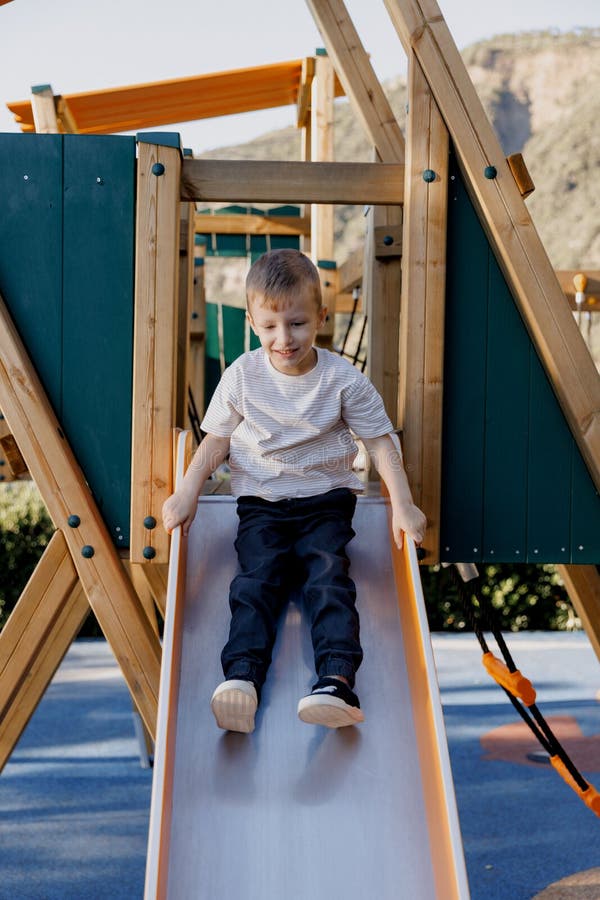 Vertical Shot of a Smiling Boy Going Down the Slide in a Playground ...