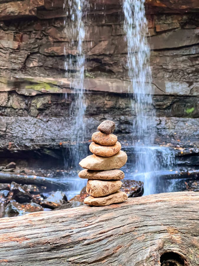 Vertical Shot of a Stack of Stones on a Log by the Waterfall in a ...
