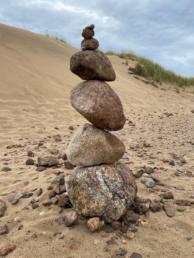 Vertical Shot of a Stack of Stones Over the Sand Under a Blue Cloudy ...