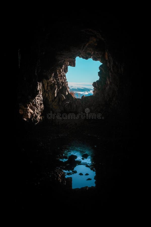 Vertical Shot of a Stone Cave Entrance Reflecting in Water Inside Stock ...