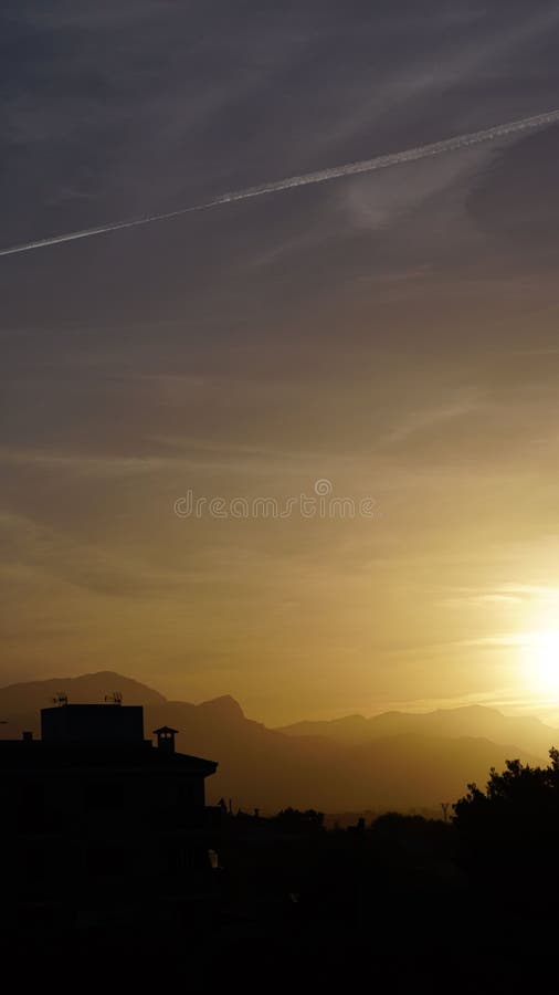 Vertical Shot of a Sunset with Clouds and a Silhouette of Buildings ...