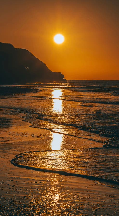 Vertical Shot of Sunset Reflected on the Waves on the Beach Stock Image ...