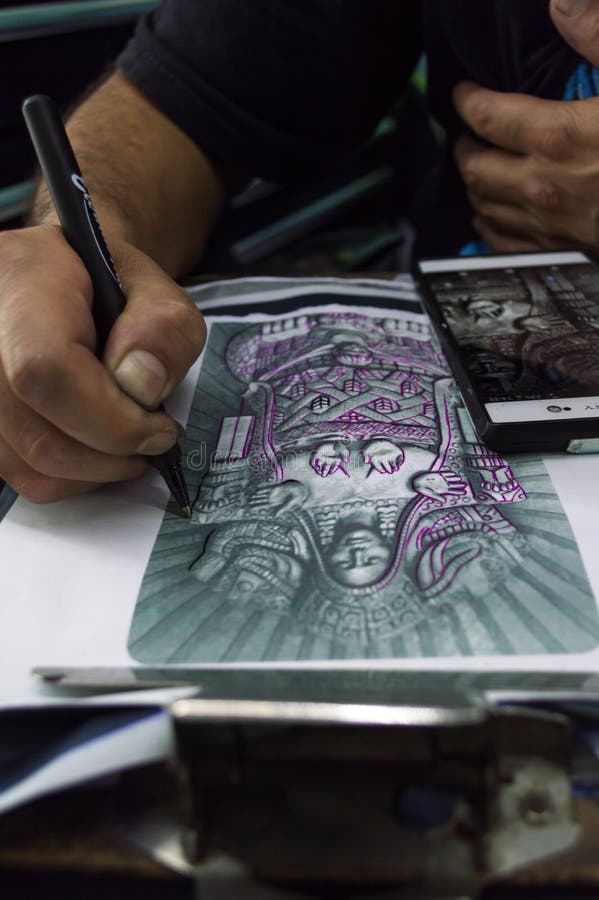 Vertical Shot of a Tattoo Artist Drawing a Tattoo Under the Lights in a ...