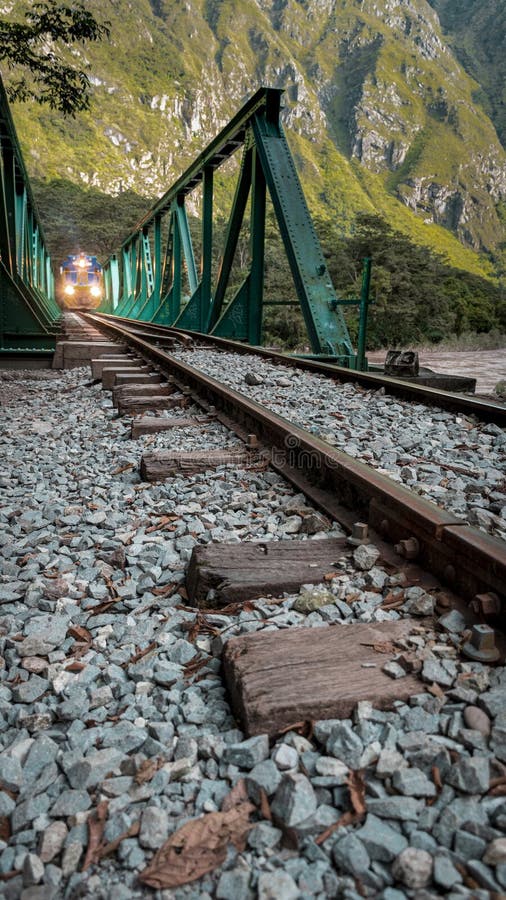 Vertical Shot of Train Tracks Near Cliffs with an Illuminated Train ...
