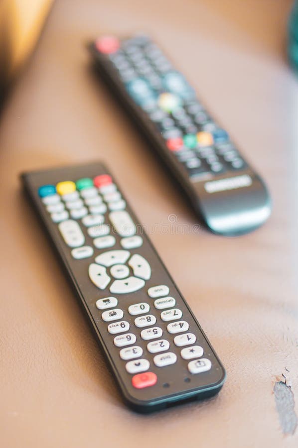 Vertical Shot of Two Branded Television Remote Controllers Laying on a ...