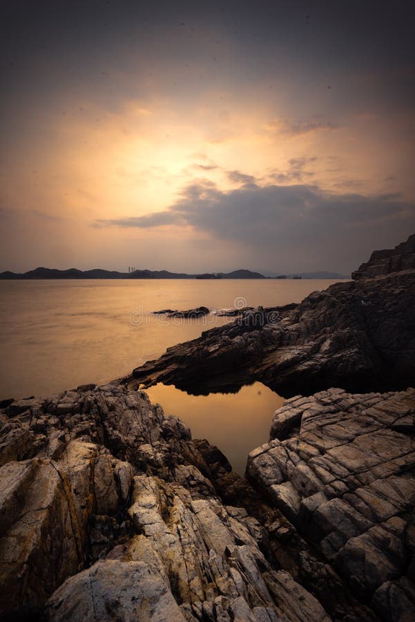 Vertical Shot of the Water and the Cliffs during a Sunset in a Clouded ...