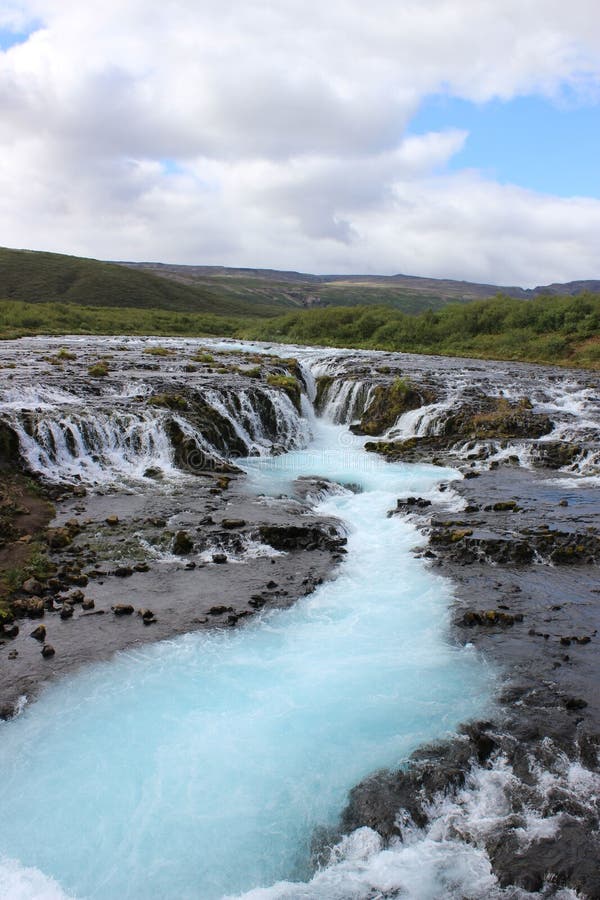 Vertical Shot of a Waterfall Cascading Downwards Surrounded by Hills ...