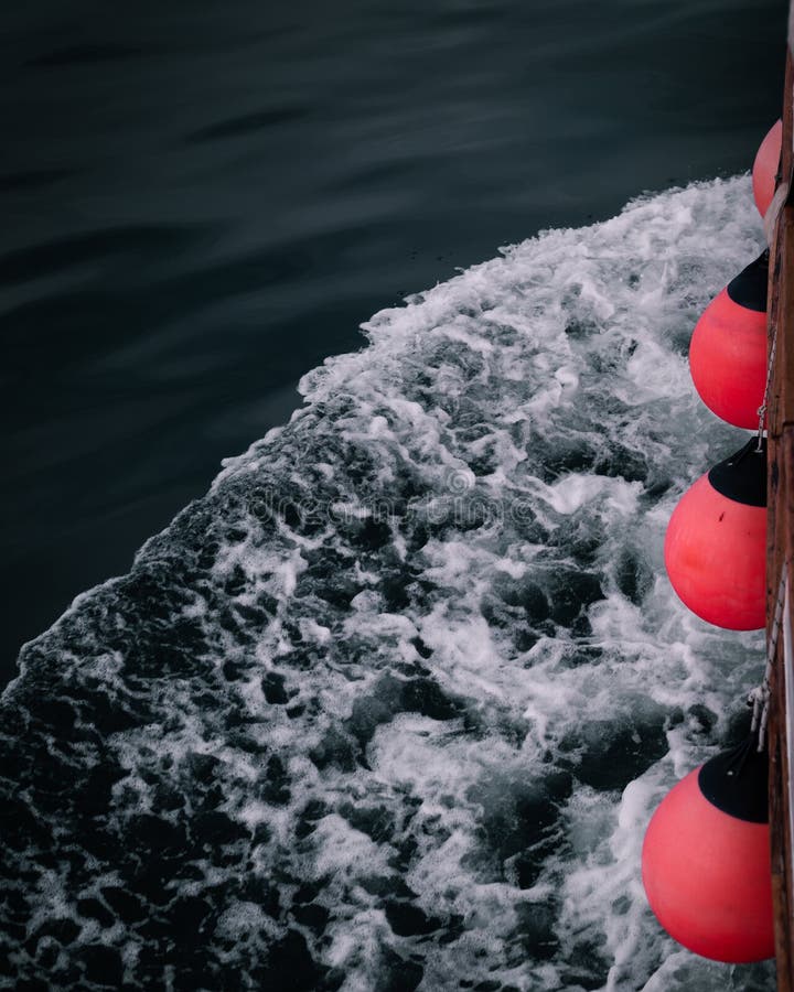 Vertical Shot of Waves Hit by a Ship with Red Buoys on the Side Stock ...