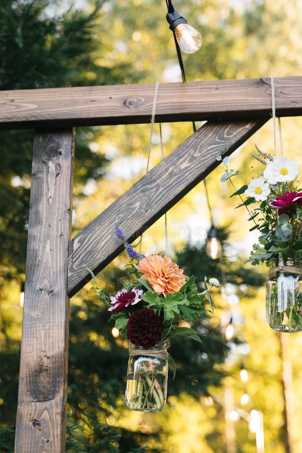 Vertical Shot of a Wedding Arbor with Floral Arrangements in a Jar ...