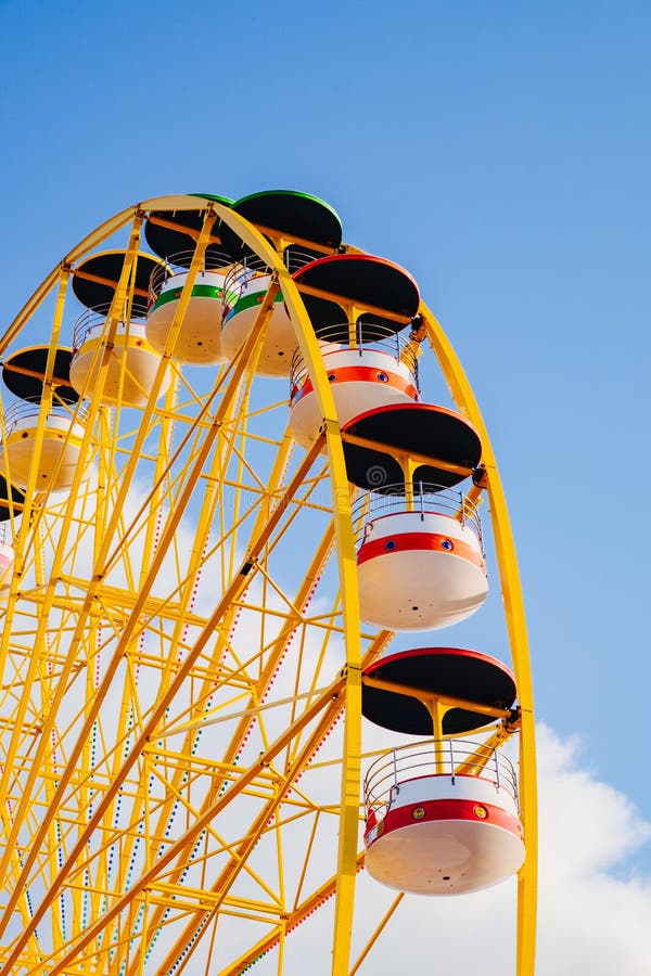Vertical Shot of a Yellow Amusement Park Wheel Under a Blue Sky Stock ...