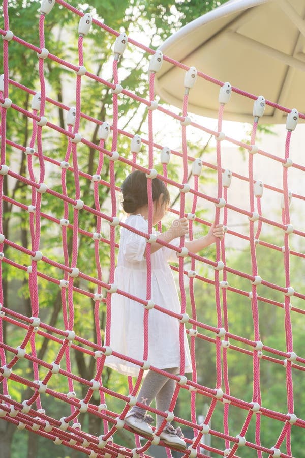 Vertical Shot of a Young Girl Playing in the Playground Monkey Ropes ...