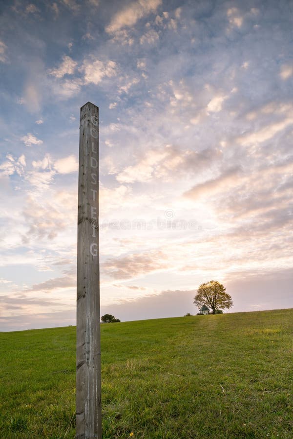 Vertical Sunset View with a Wooden Pillar in a Field with a Chapel and ...