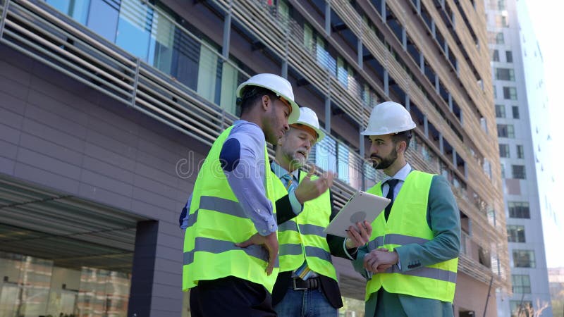 Three Construction Engineers Having a Discussion on Building Site ...