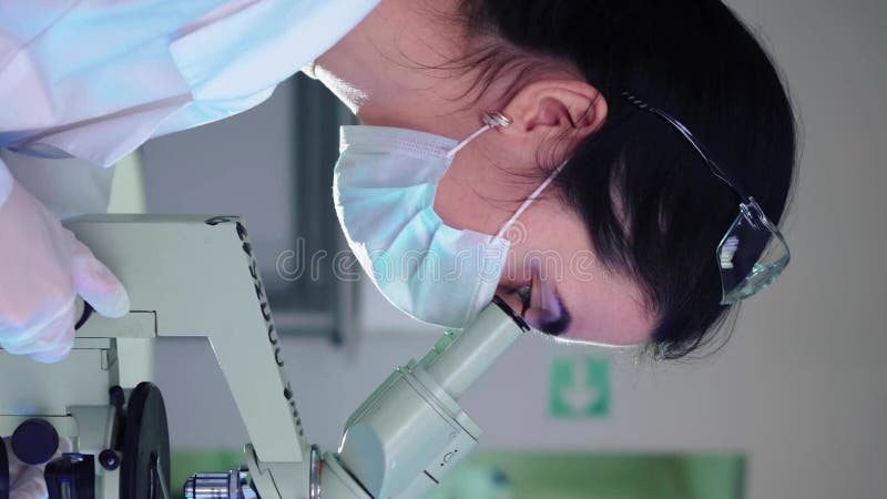 Female Microbiologist Looking into Microscope in Medical Science ...