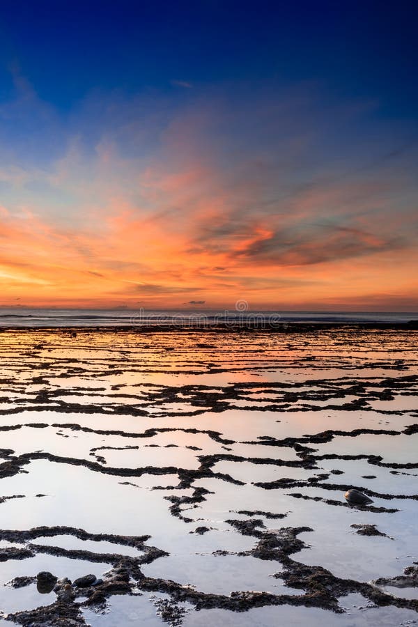 Vertical View of a Beautiful Sunset Over the Ocean with Rocky Beach and ...