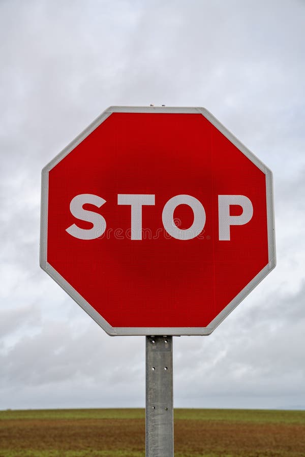 Vertical View of a Bright Red Stop Sign with a Gray Overcast Sky Behind ...