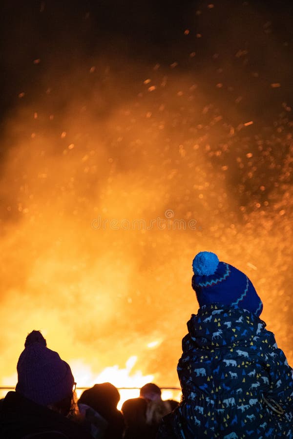 Vertical View of a Child and Crowd before the Roaring Bonfire Flames at ...