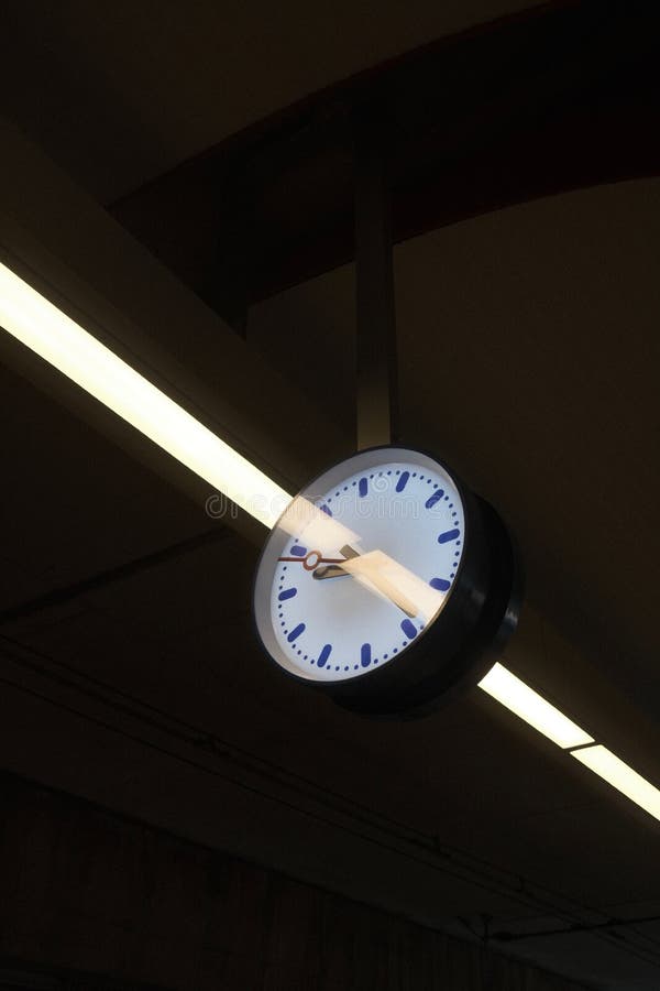 Vertical View of a Hanging Clock with Light on it Stock Image - Image ...