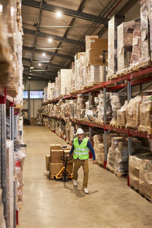 Vertical View at Warehouse Interior with Worker Pulling Cart in Row ...