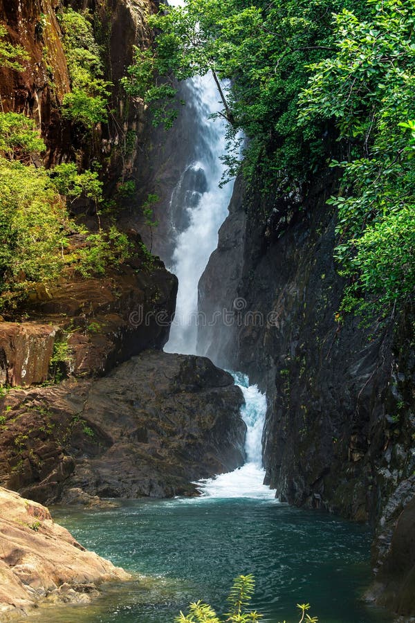 Vertical of a Waterfall Cascading Down the Green Rocks Stock Image ...