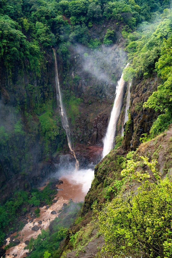 Vertical of a Waterfall Cascading Down a Rock Covered with Greenery ...