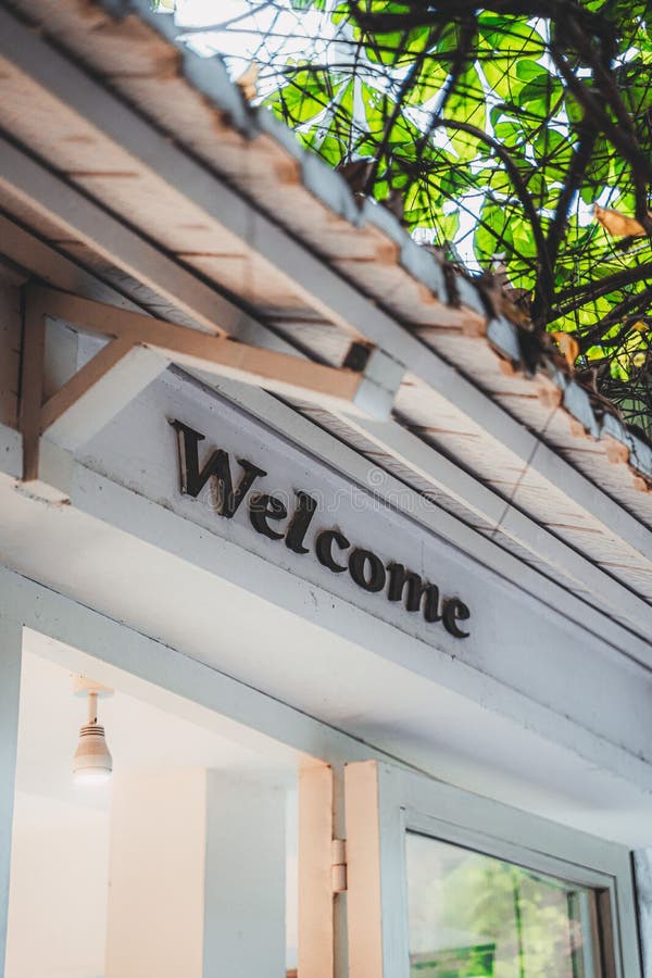 Vertical of the "Welcome" Text with Black Letters on the Wall, Trees ...