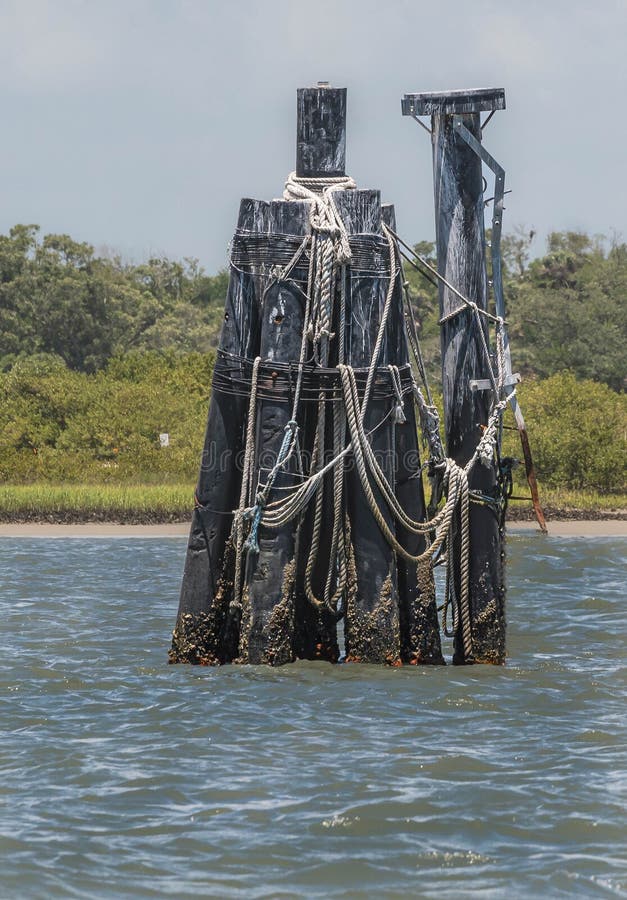 Vertical of Wooden Pillars Wrapped with a Rope in a Lake Stock Photo ...