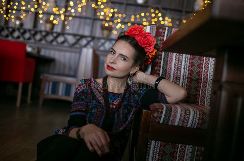 Vertikalt Foto Av En Flicka I Nationella Kläder Som Sitter På Golvet