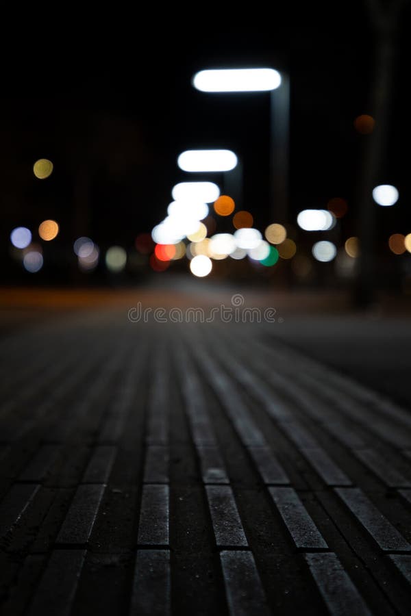 Very Close Up Low Angle View of a Sidewalk with City Lights Blurred in ...