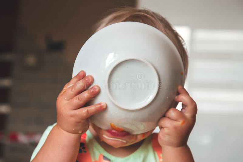 A Very Hungry Boy Enthusiastically Eats from a Plate Holding it with ...