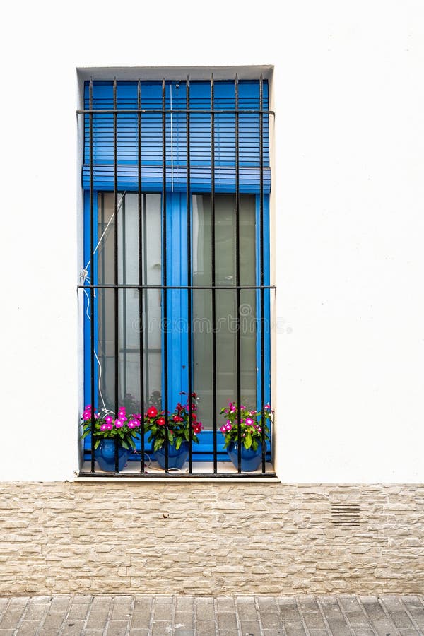 Vibrant Blue Window with Flower Pots and Iron Bars on a White Wall ...