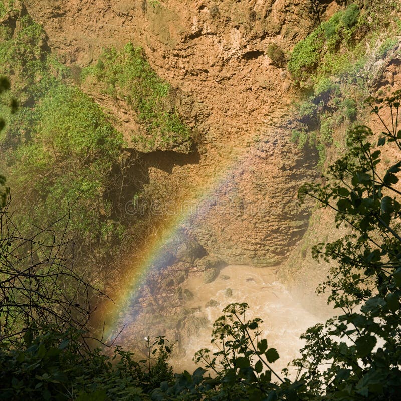A Vibrant Rainbow Appears through Mist Rising from a Waterfall. Stock ...