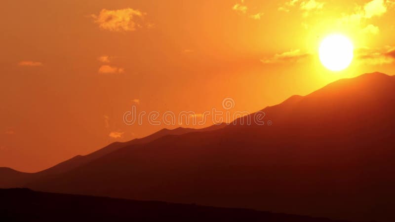 Vibrant Sunset Over a Mountain Range, with the Sun Casting a Warm Orange Glow Across the Sky and ...