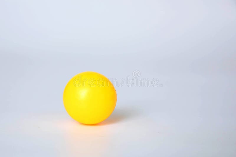 A Vibrant Yellow Ping Pong Ball Resting on a Light Grey Background ...