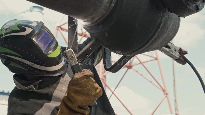 Video 4k. Worker in Full Welding Gear, Performing Pipe Welding Amidst ...