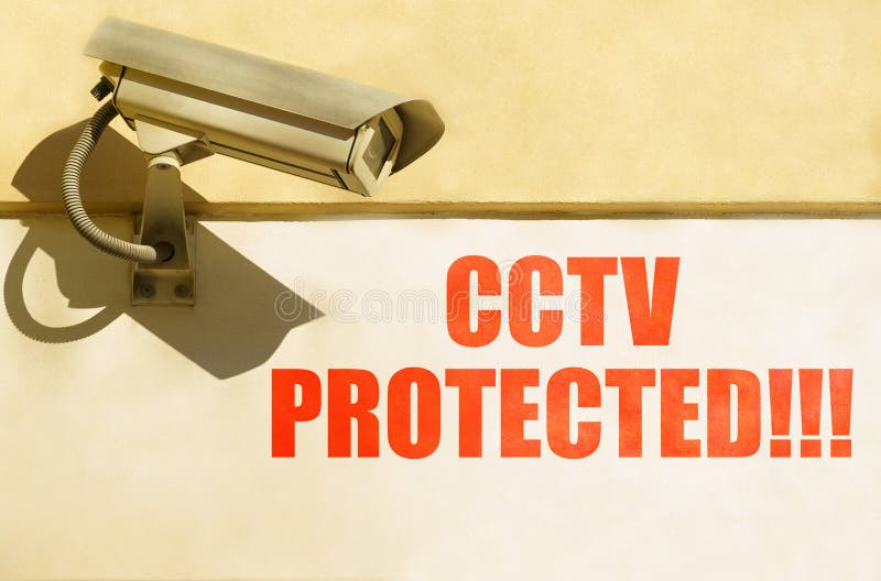 A CCTV Camera is Installed on the Wall of the Building, Next To it is ...