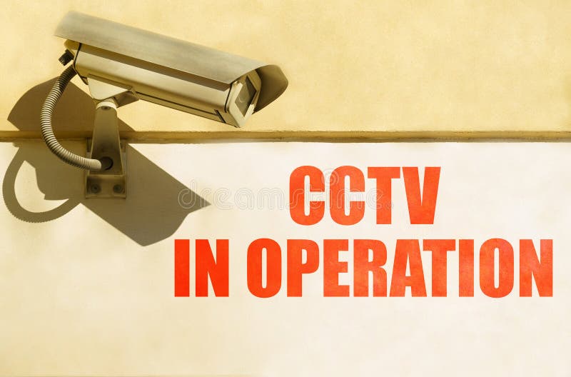 A CCTV Camera is Installed on the Wall of the Building, Next To it is ...