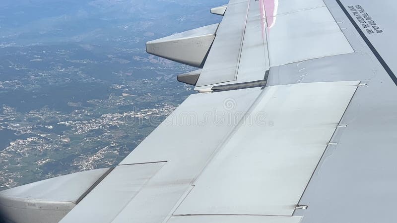 View from Airplane Window Showing Wing and Landscape Below during ...