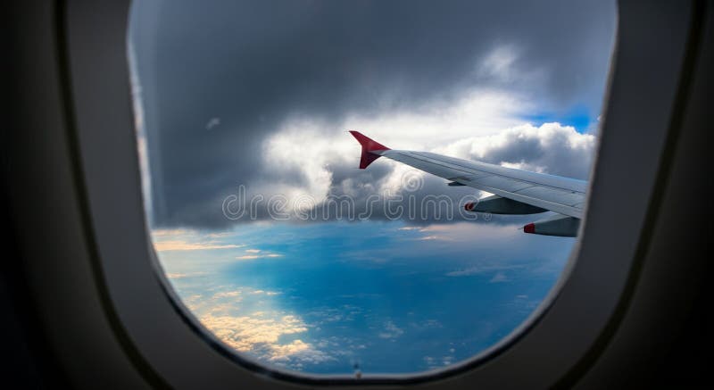 View from an Airplane Window Showing a Wing with a Red Tip Against a ...