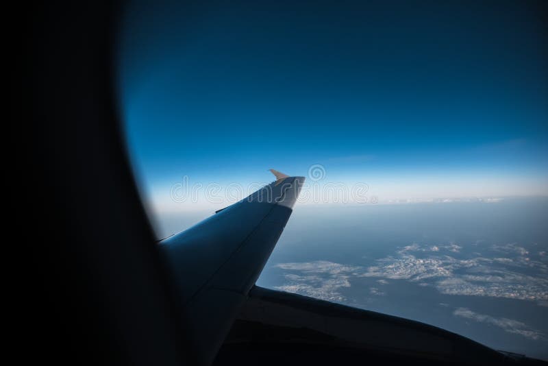 View of Airplane Wing through Window. Flying Above the Clouds Stock ...