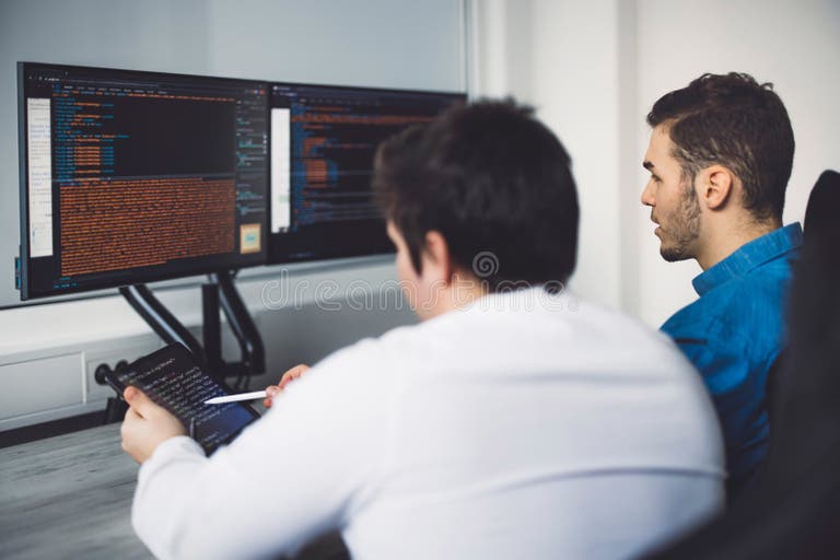 View from the Back Two Male it Programmers Working on Desktop Computers and a Tablet, Coding ...