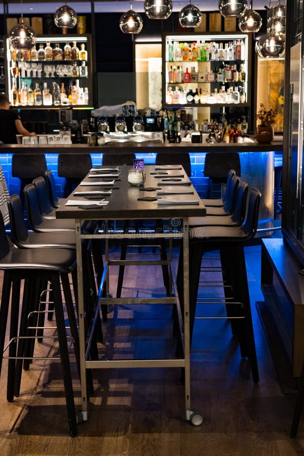 View of a Bar: Blue Lights, Bar Table and Bar Stools, Counter, Drinks ...