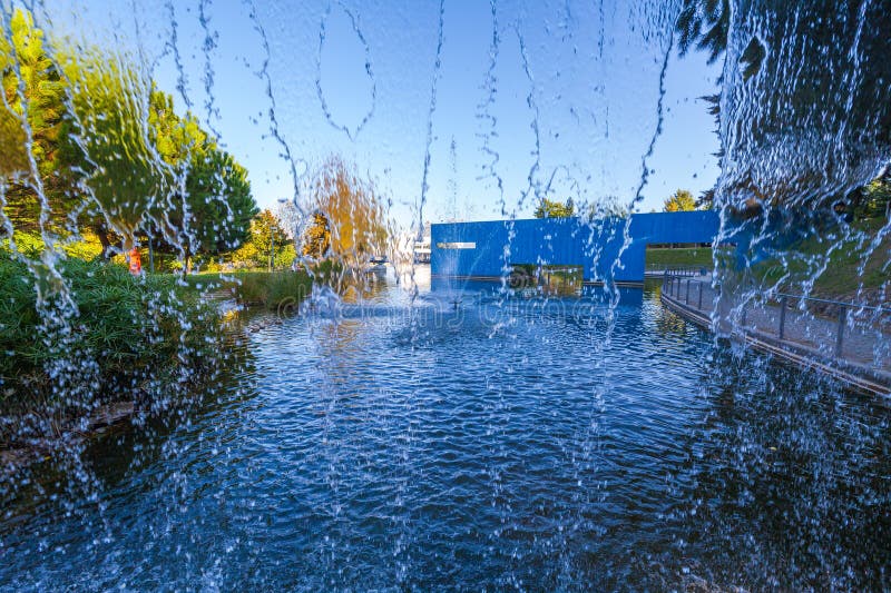 A View through a Cascading Waterfall Onto a Pond with a Fountain Stock ...