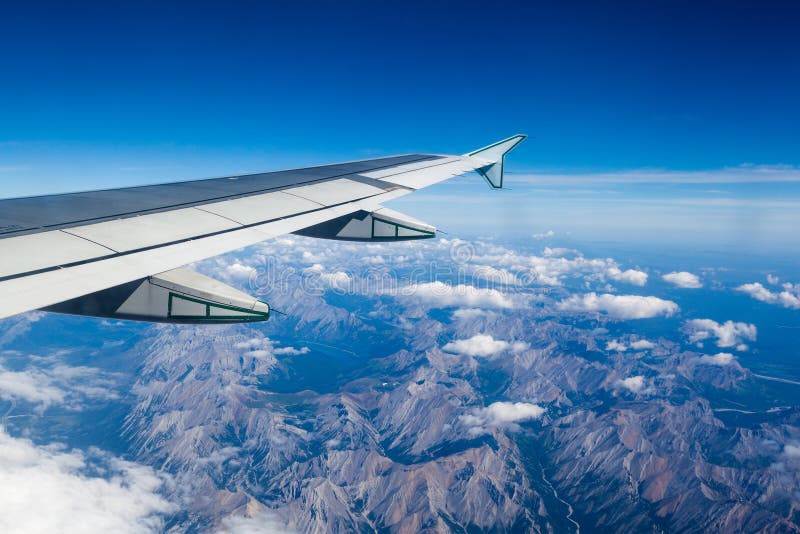 View of Clouds and Rocky Mountains Outside Airplane Window Stock Image ...