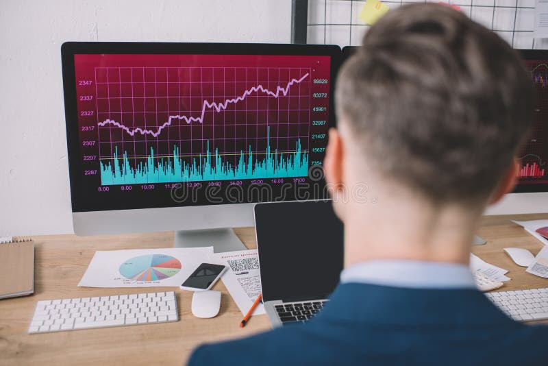 View of Data Analyst Sitting at Table with Computers and Papers with ...
