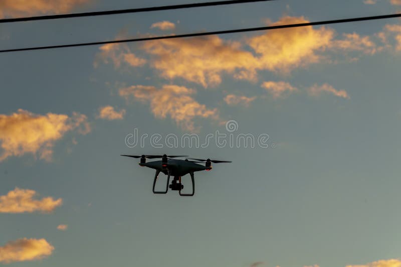 View of a Drone Landing during Sunset with Blue Sky and Golden Clouds ...