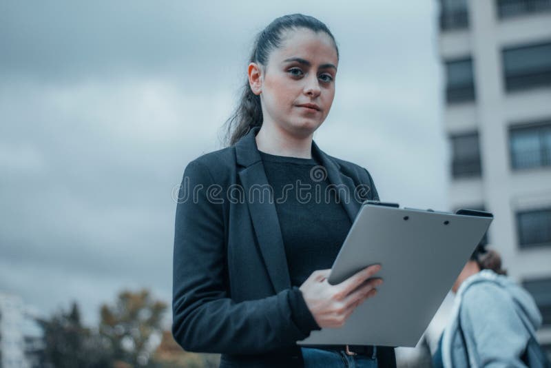 View of a Female Student Holding a Clipboard while Standing Outdoors ...